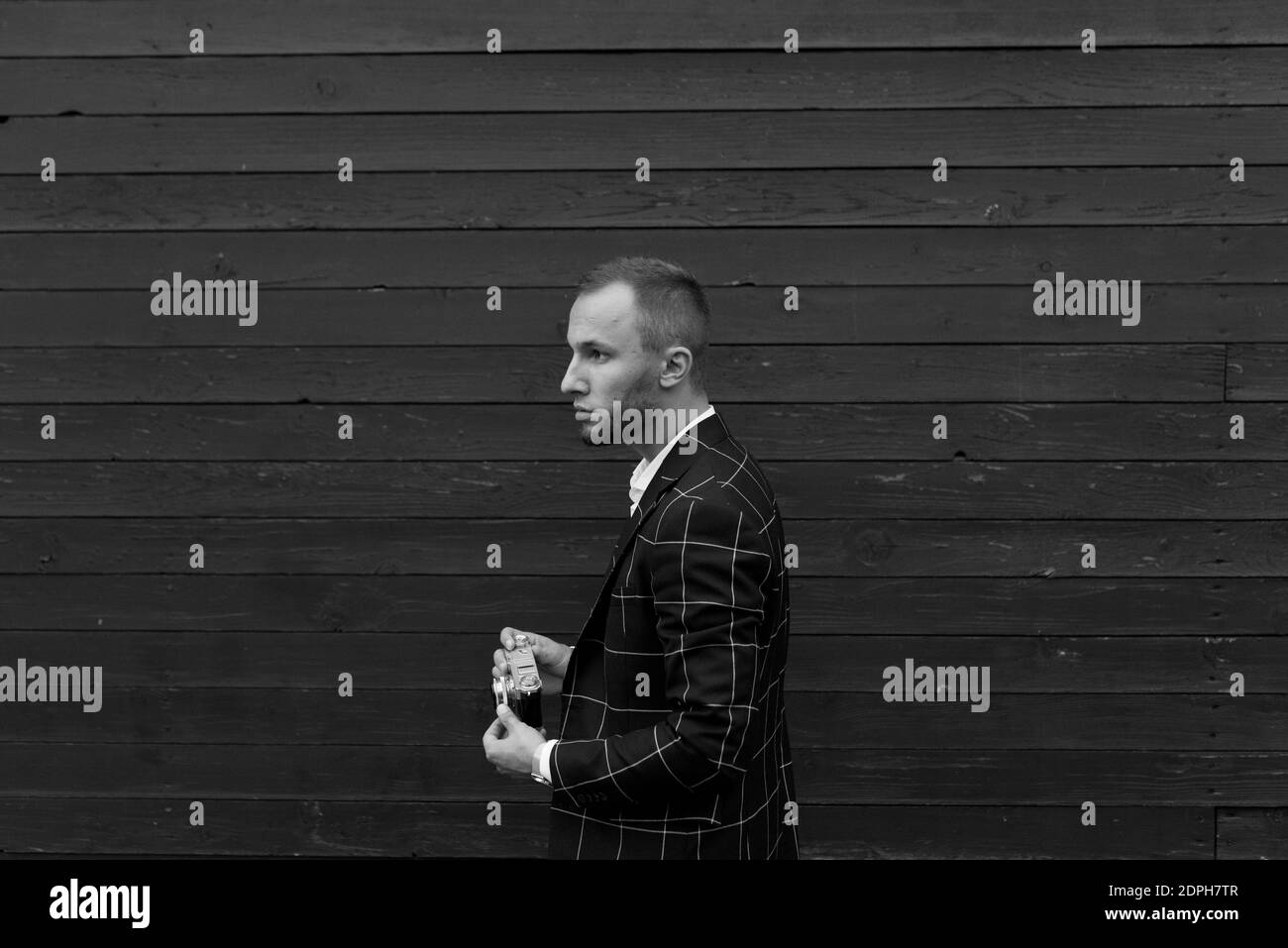 Young Man Looking Away Holding Camera While Standing Against Wall Stock ...