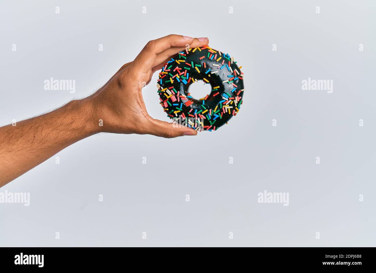 Hand of hispanic man holding chocolate donut over isolated white ...