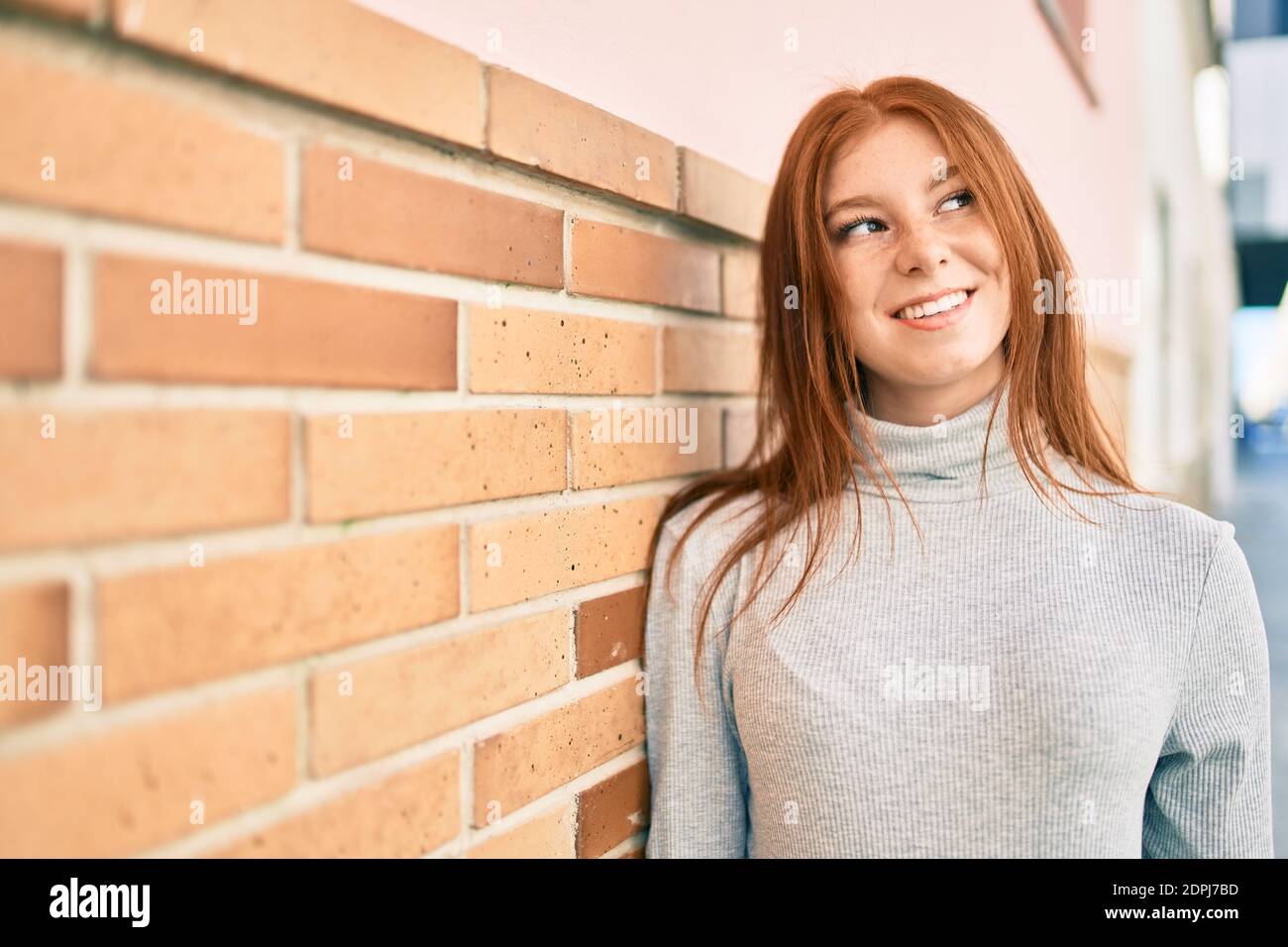 Young irish teenager girl smiling happy leaning on the wall at the city ...