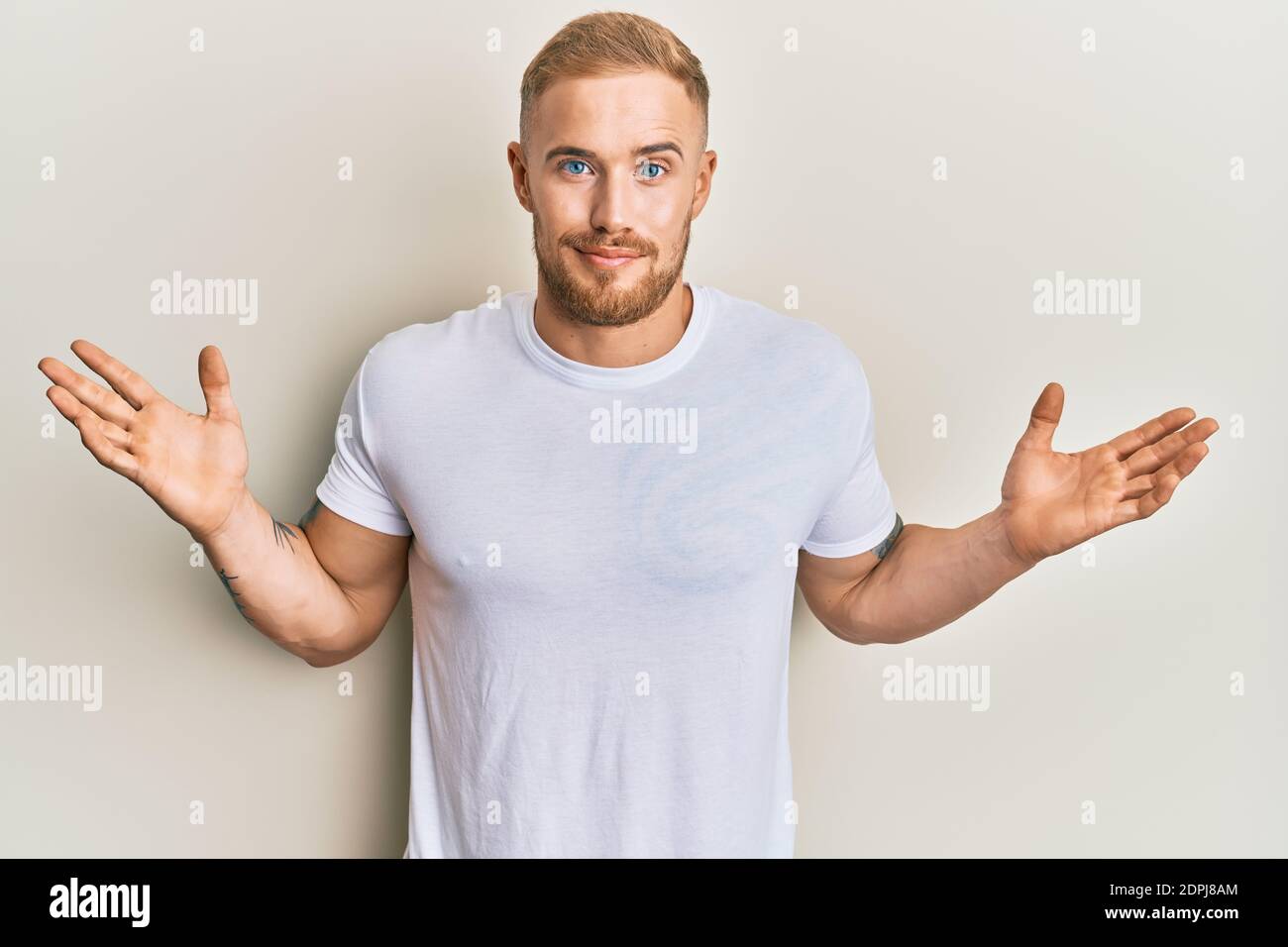 Young caucasian man wearing casual white tshirt clueless and confused ...