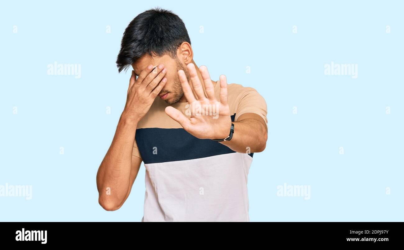 Young handsome man wearing casual clothes covering eyes with hands and ...