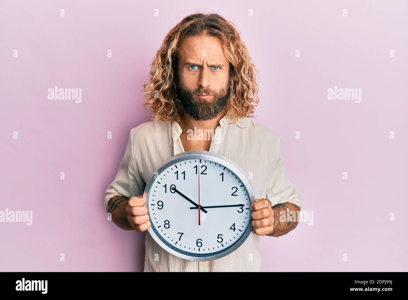 Handsome man with beard and long hair holding big clock skeptic and ...