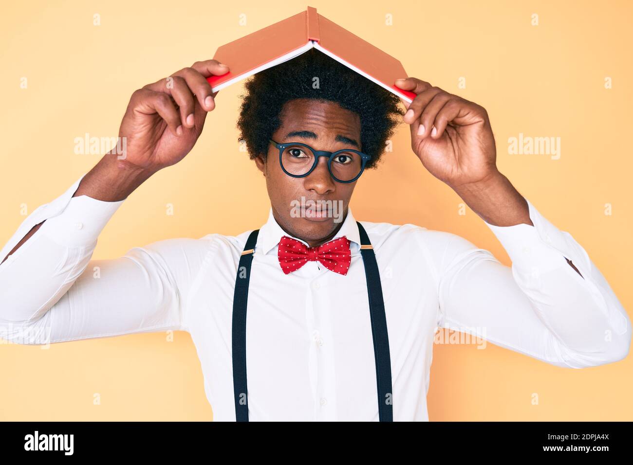 Handsome african american nerd man with afro hair holding book over ...