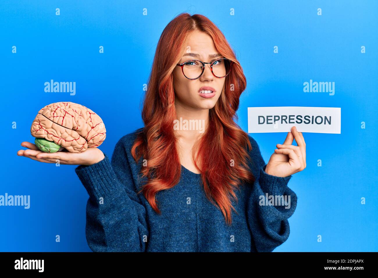 Young redhead woman holding brain and depression text clueless and ...