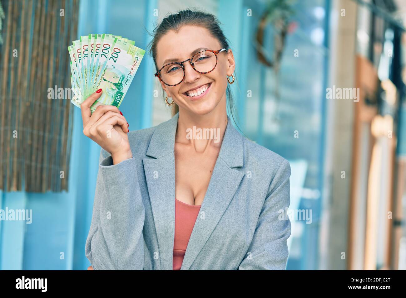 Young blonde businesswoman smiling happy holding russian 200 ruble ...