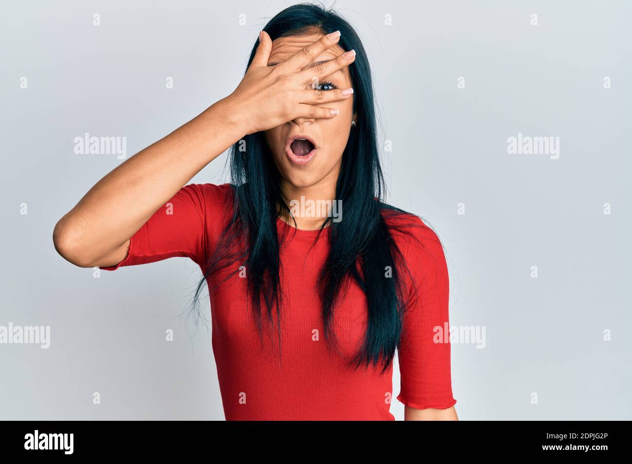 Beautiful hispanic woman wearing casual clothes peeking in shock ...