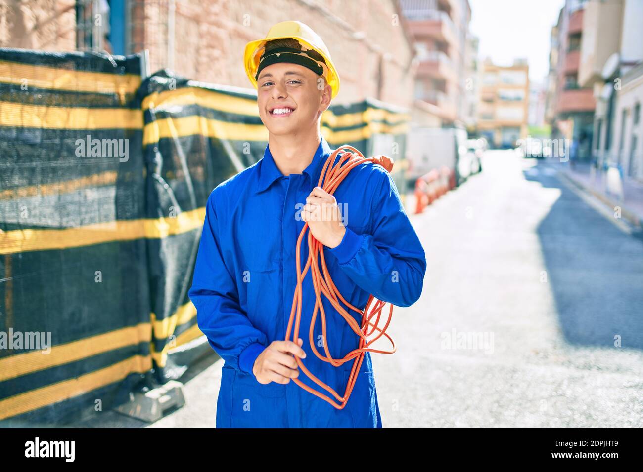 Young hispanic workman smiling happy holding electrical cable at street ...
