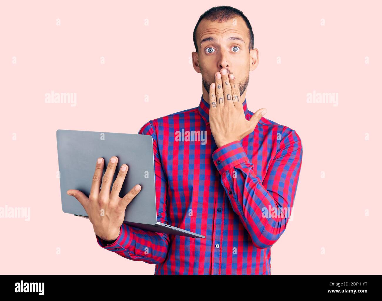 Young handsome man working using computer laptop covering mouth with ...
