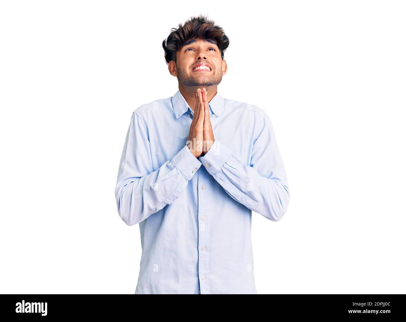 Young hispanic man wearing casual shirt begging and praying with hands ...