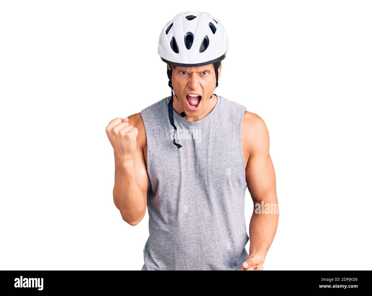 Young handsome man wearing bike helmet angry and mad raising fist ...