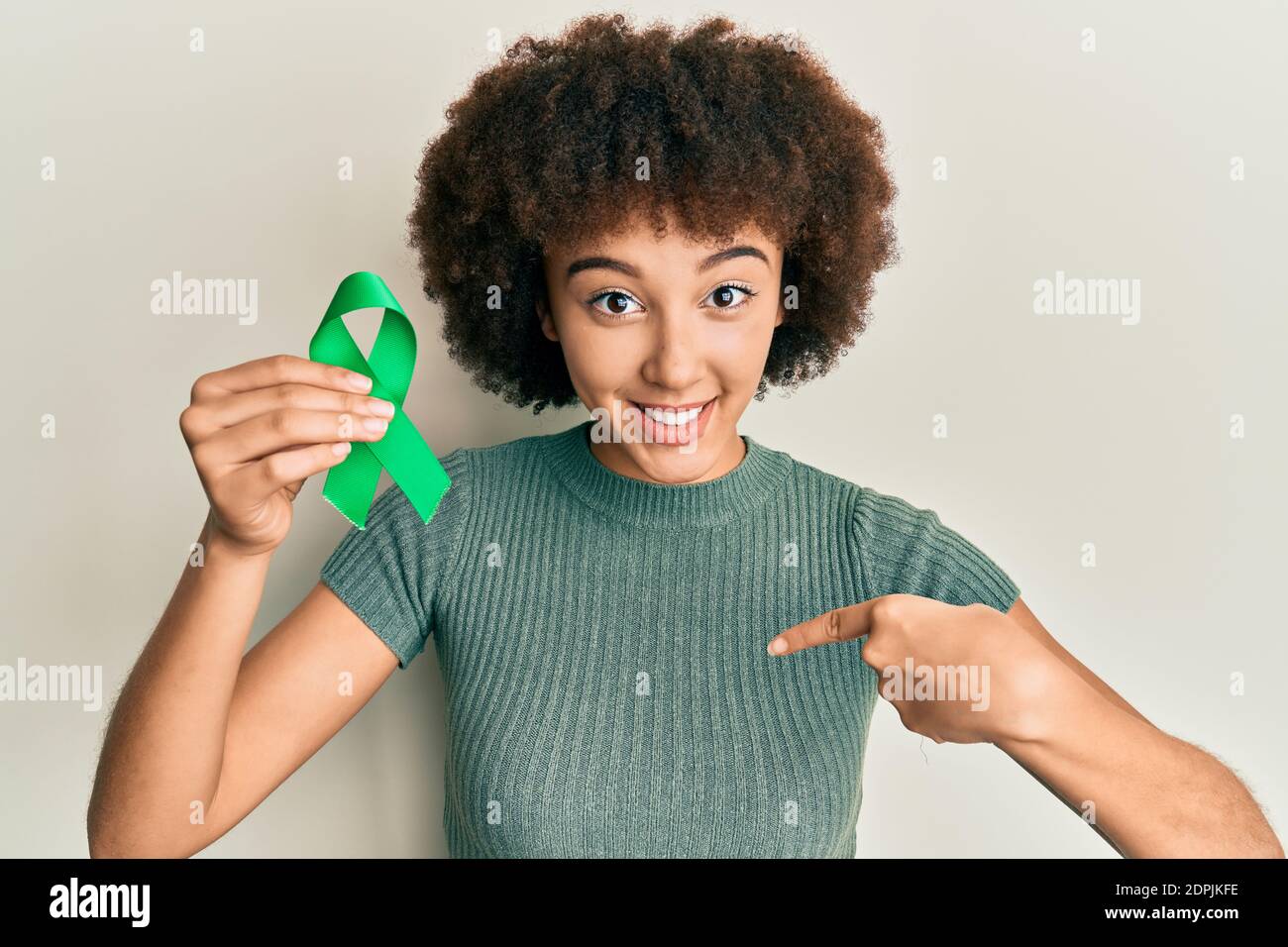 Young hispanic girl holding support green ribbon pointing finger to one ...