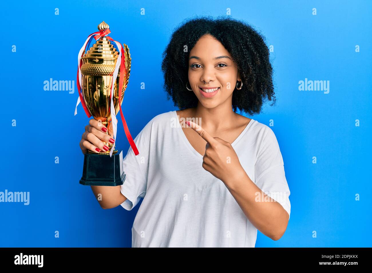 Young african american girl holding winner trophy smiling happy ...