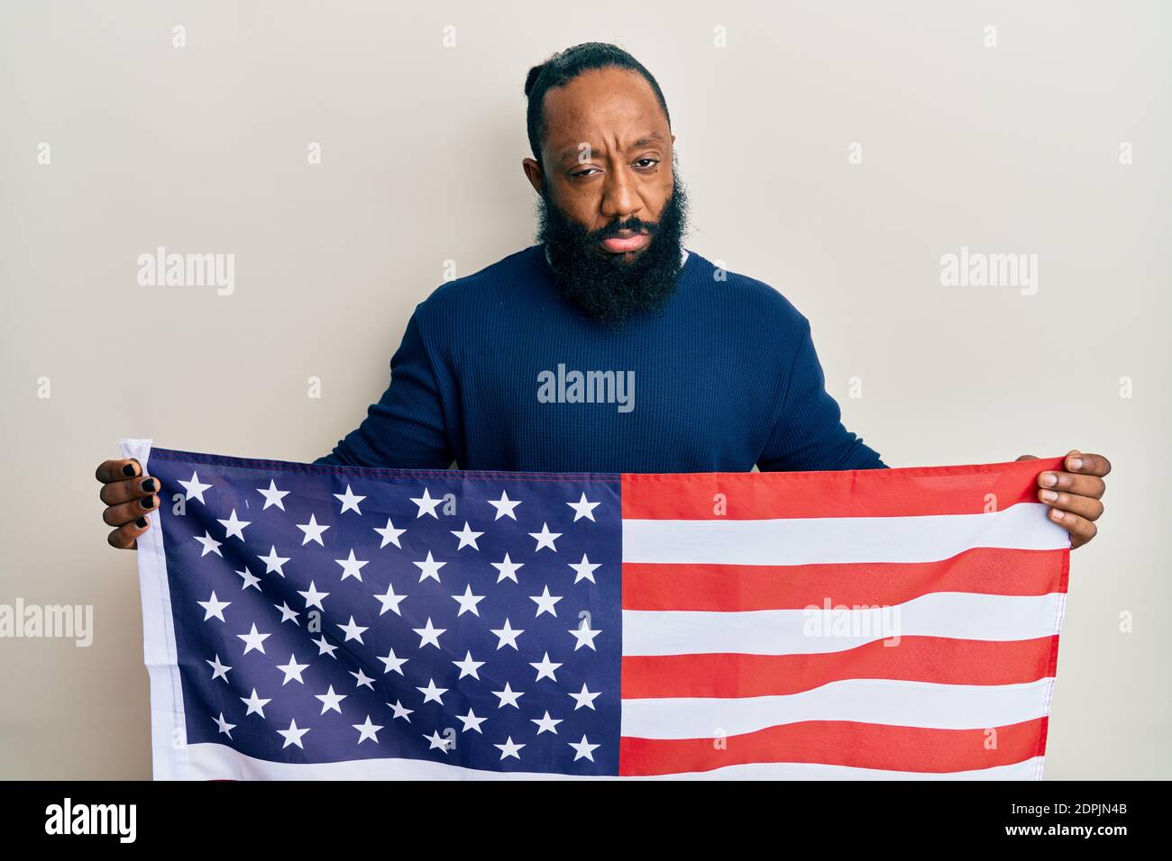 Young african american man holding united states flag depressed and ...