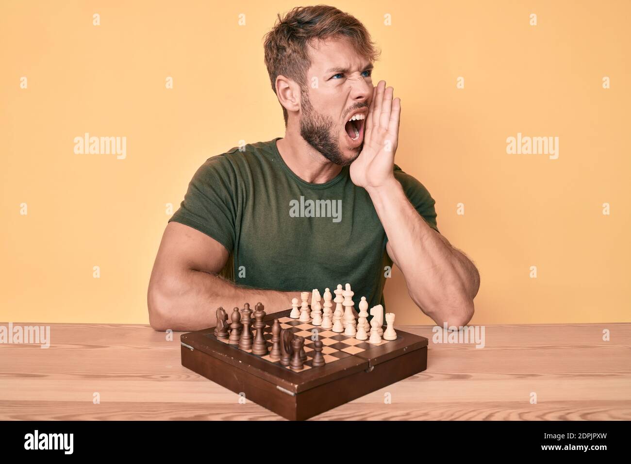 Young caucasian man playing chess sitting on the table shouting and ...