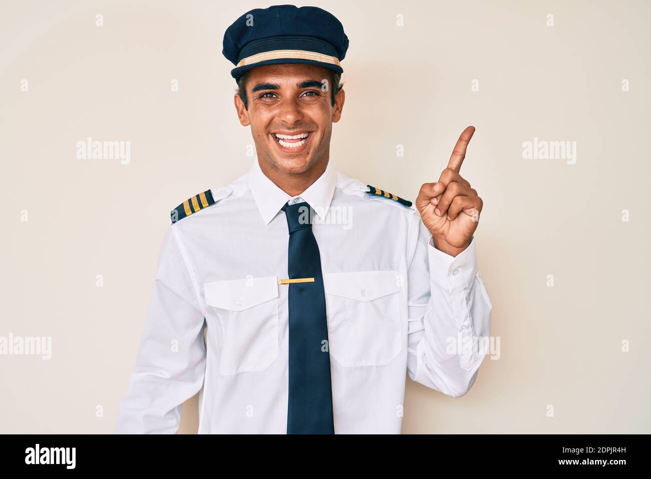 Young hispanic man wearing airplane pilot uniform with a big smile on ...