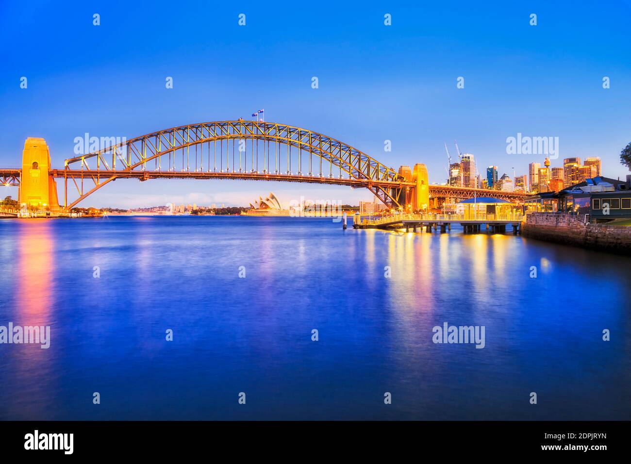 Steel arch of Sydney harbour bridge at sunset in bright illumination ...
