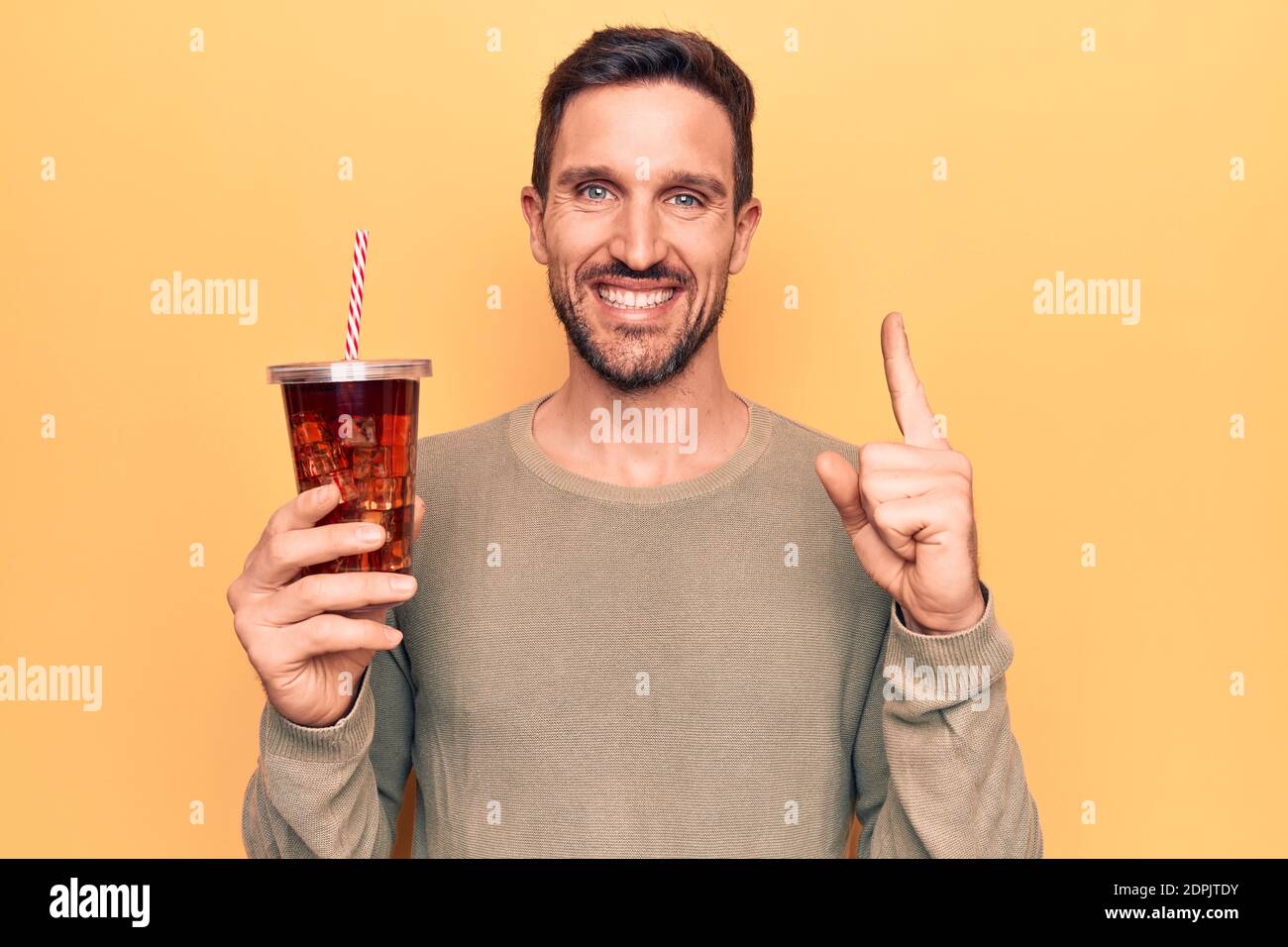 Young handsome man drinking cola refreshment beverage over isolated ...