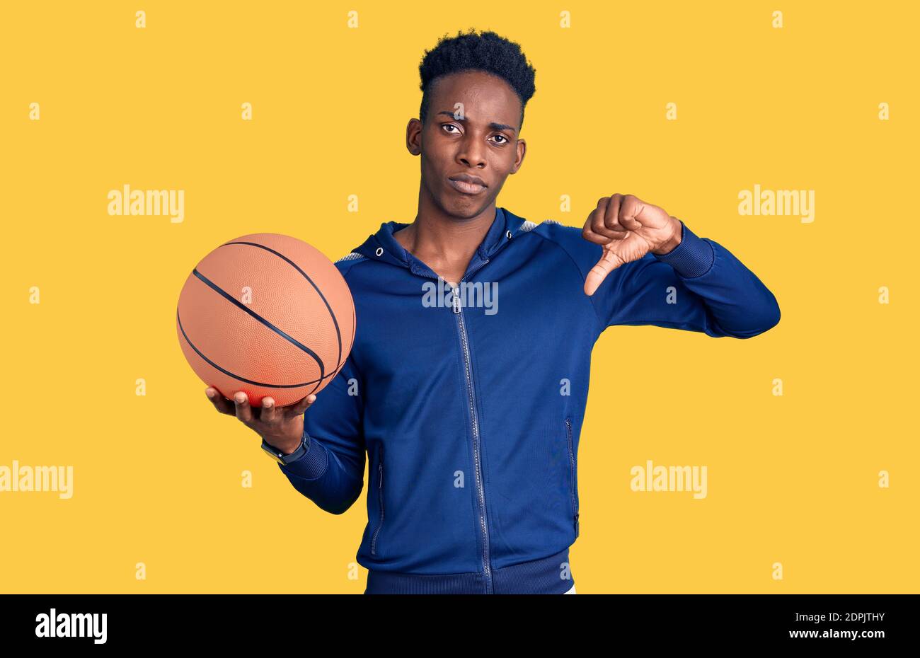 Young african american man holding basketball ball with angry face ...