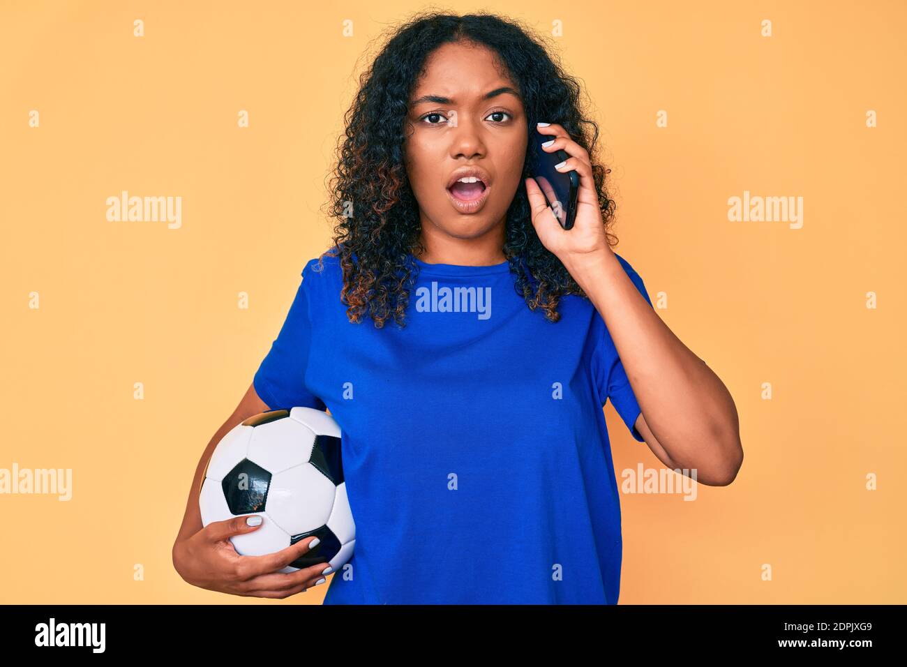 Young african american woman holding football ball talking on the ...