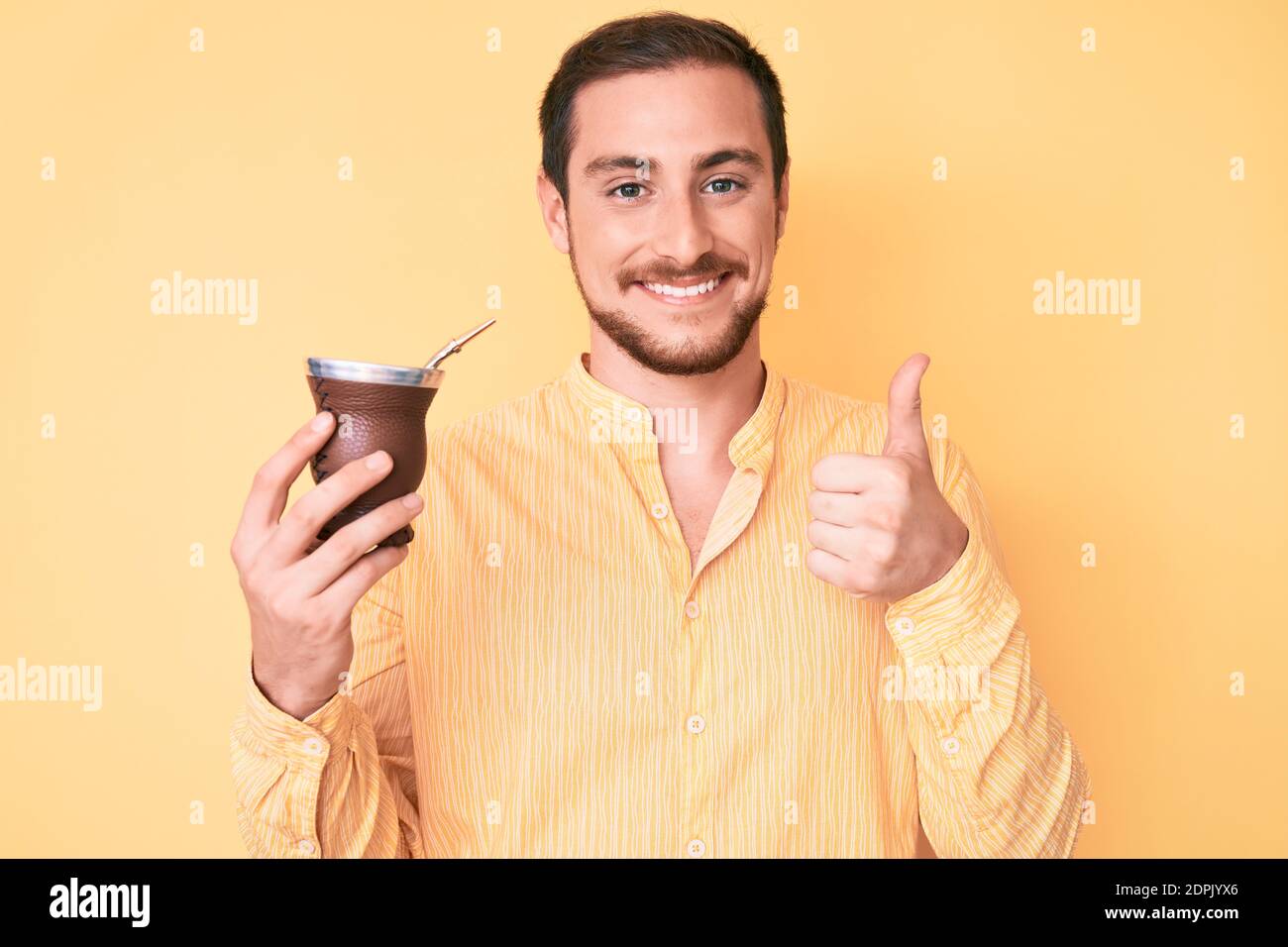 Young handsome man drinking mate infusion smiling happy and positive ...