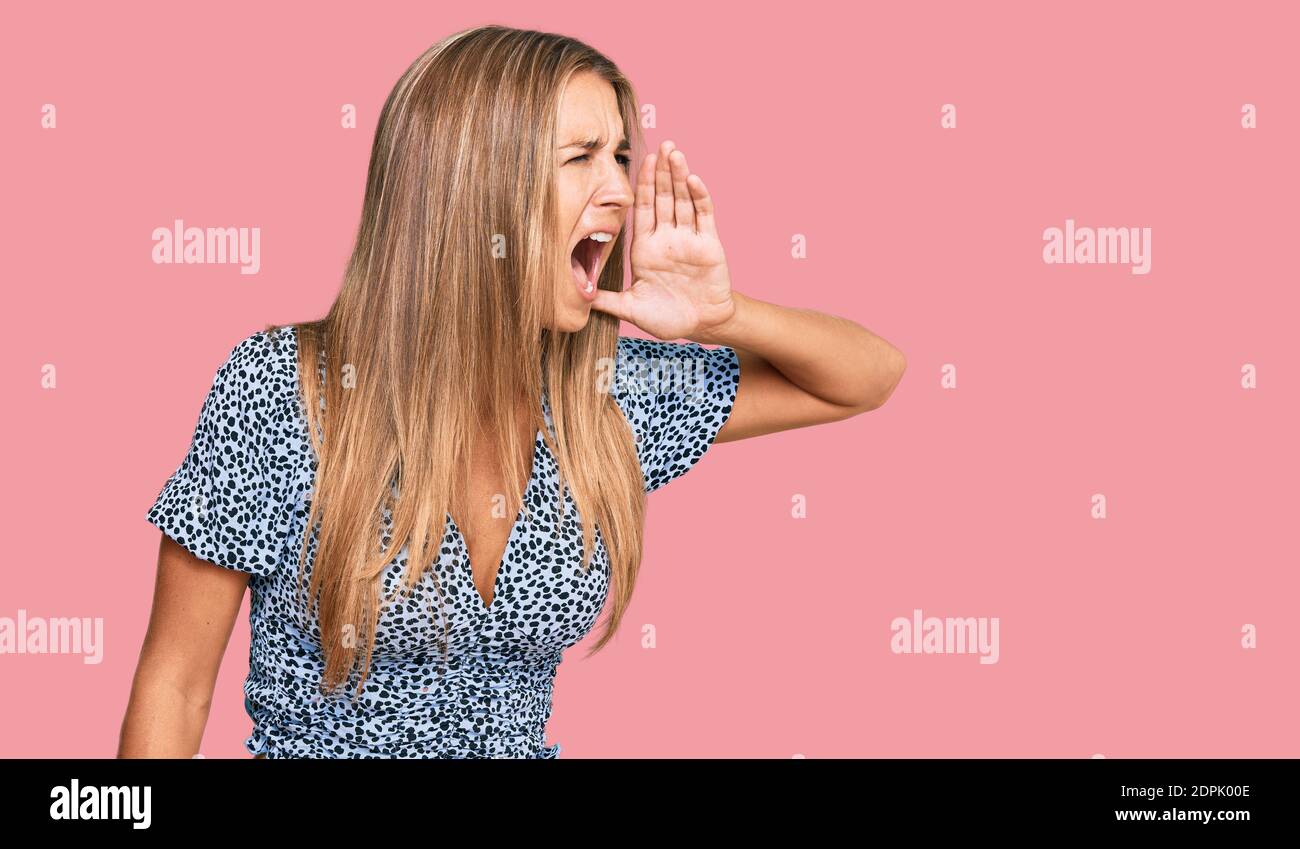 Young blonde woman wearing casual clothes shouting and screaming loud ...
