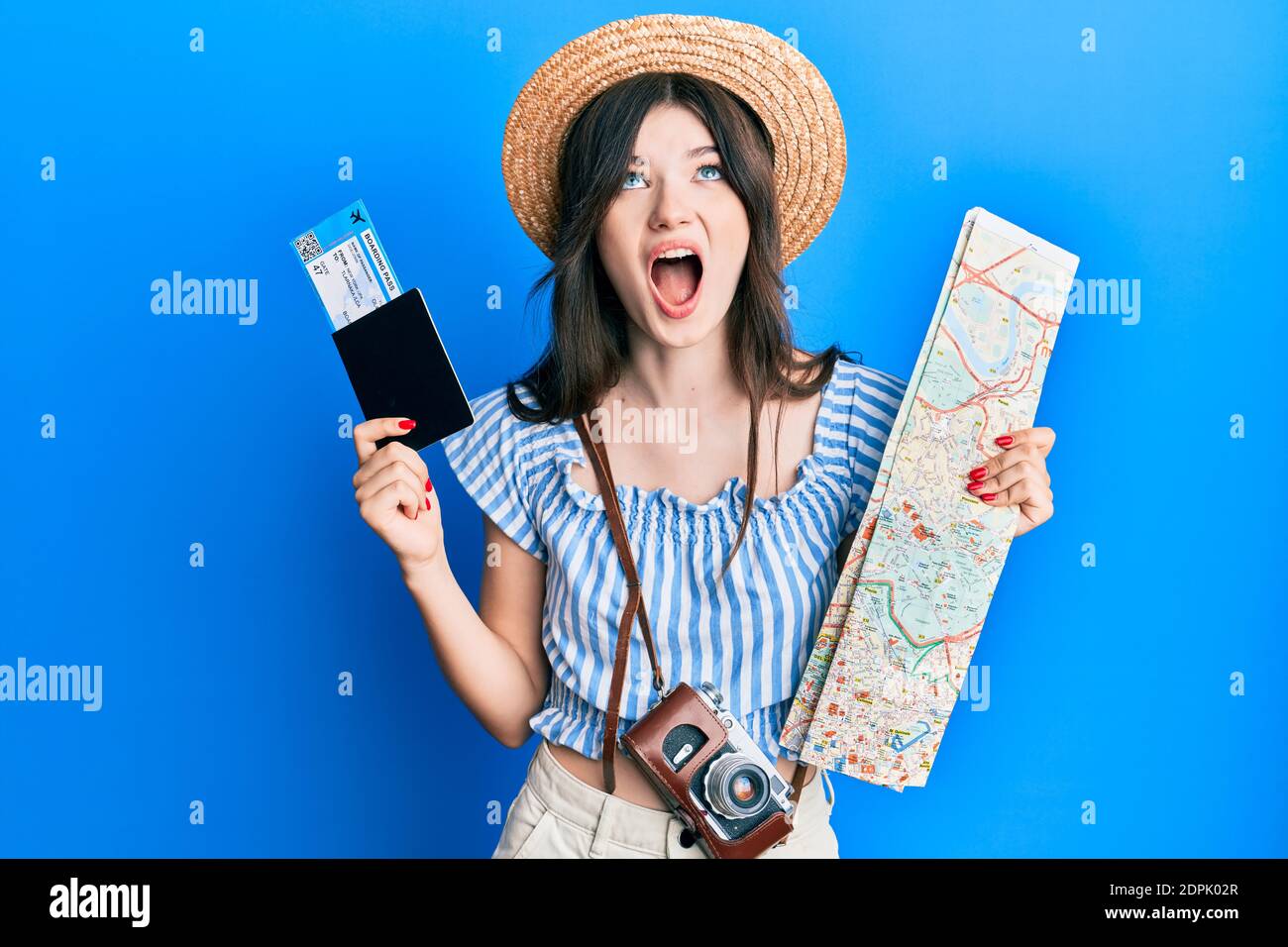 Young beautiful caucasian girl holding passport and city map angry and ...