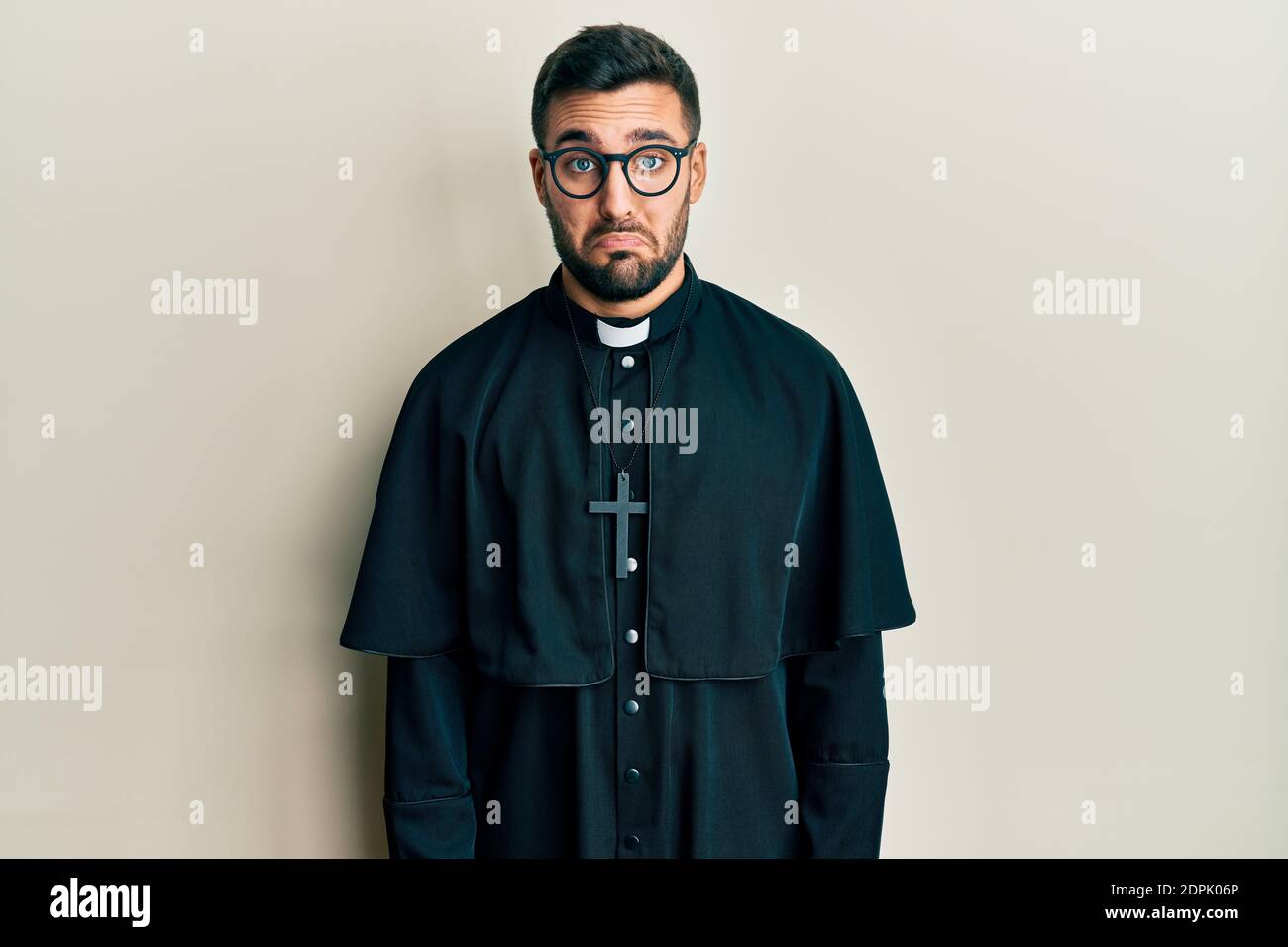 Young hispanic man wearing priest uniform standing over white ...