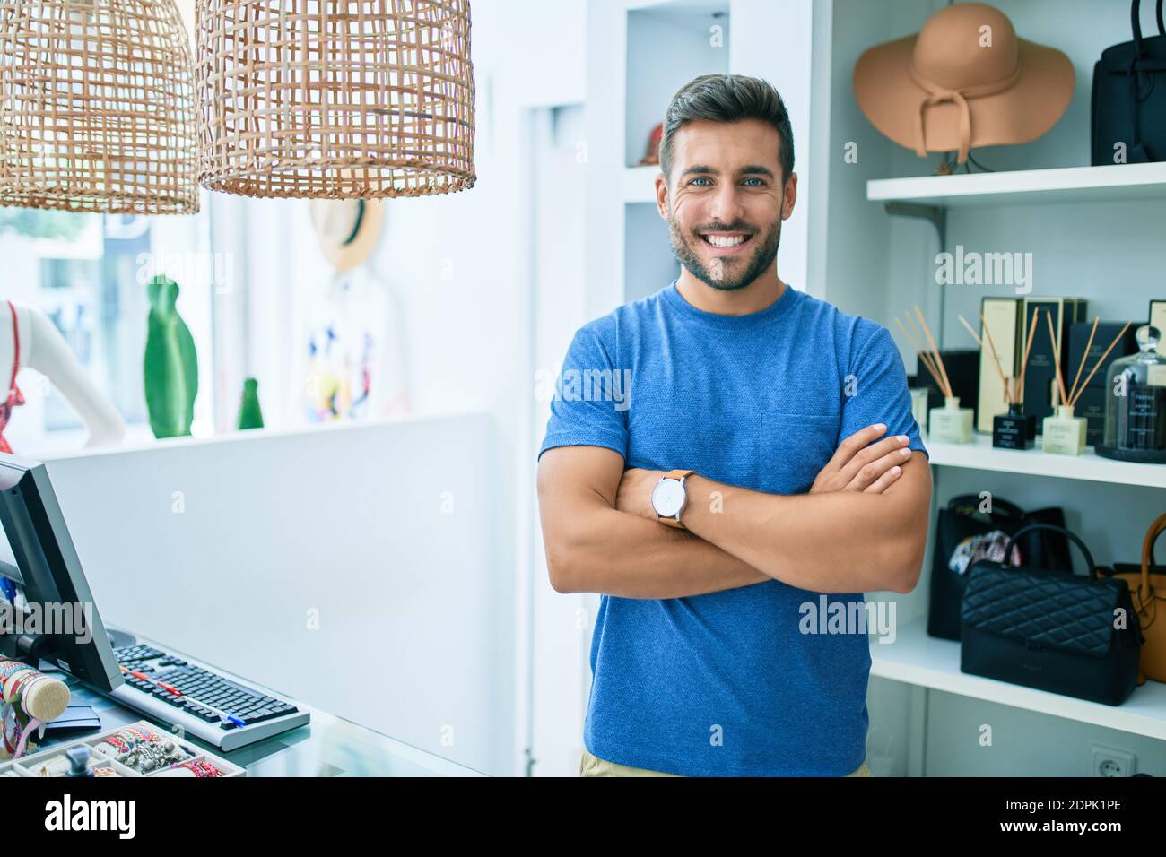 Young handsome shopkeeper smiling happy standing at clothing store ...