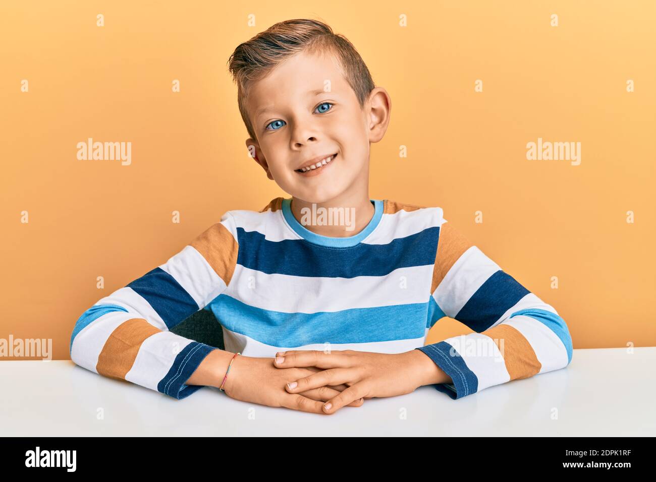 Adorable caucasian kid wearing casual clothes sitting on the table with ...