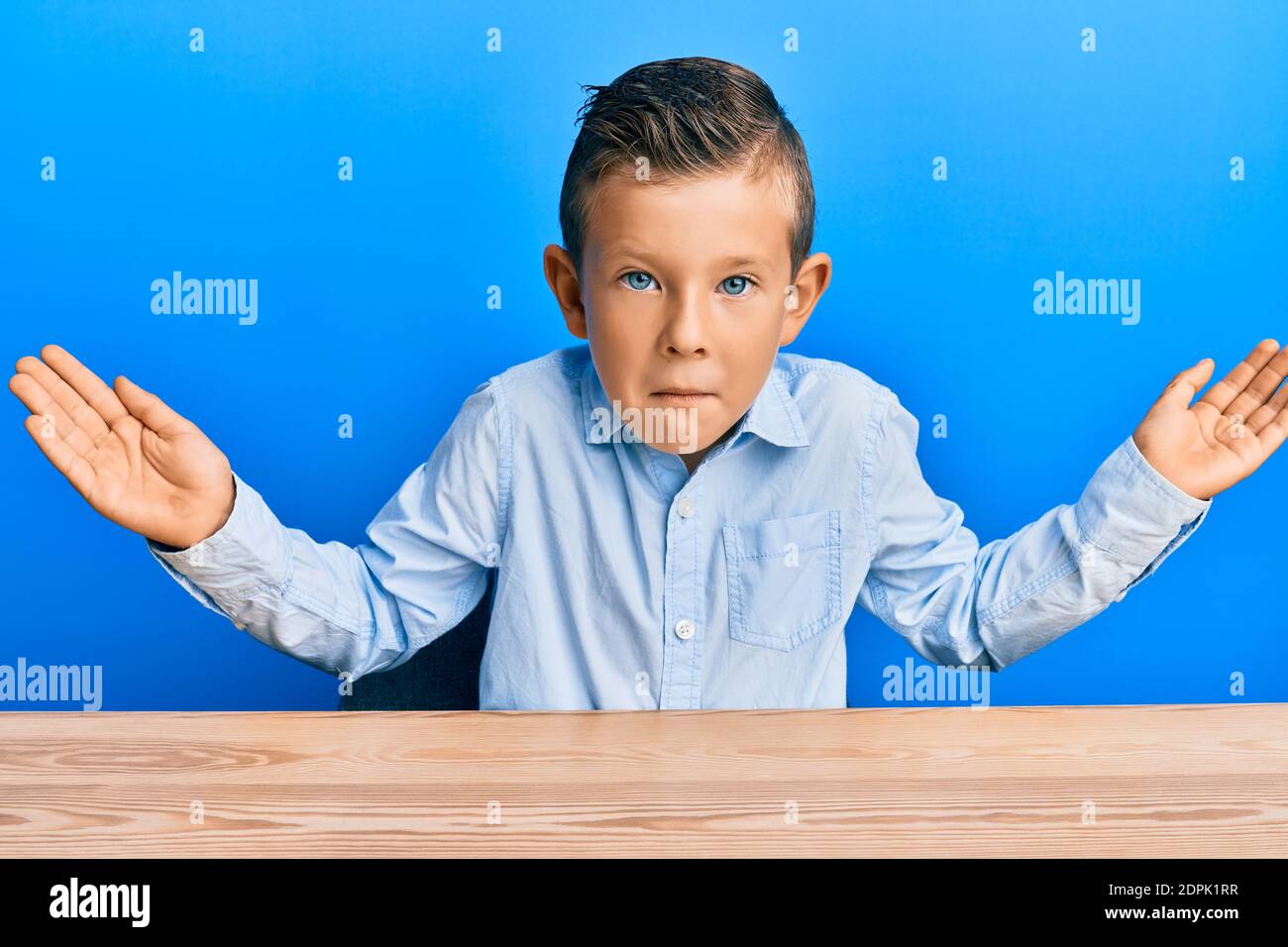 Adorable caucasian kid wearing casual clothes sitting on the table ...