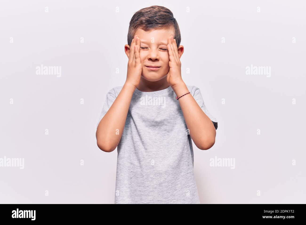 Cute blond kid wearing casual clothes suffering from headache desperate ...