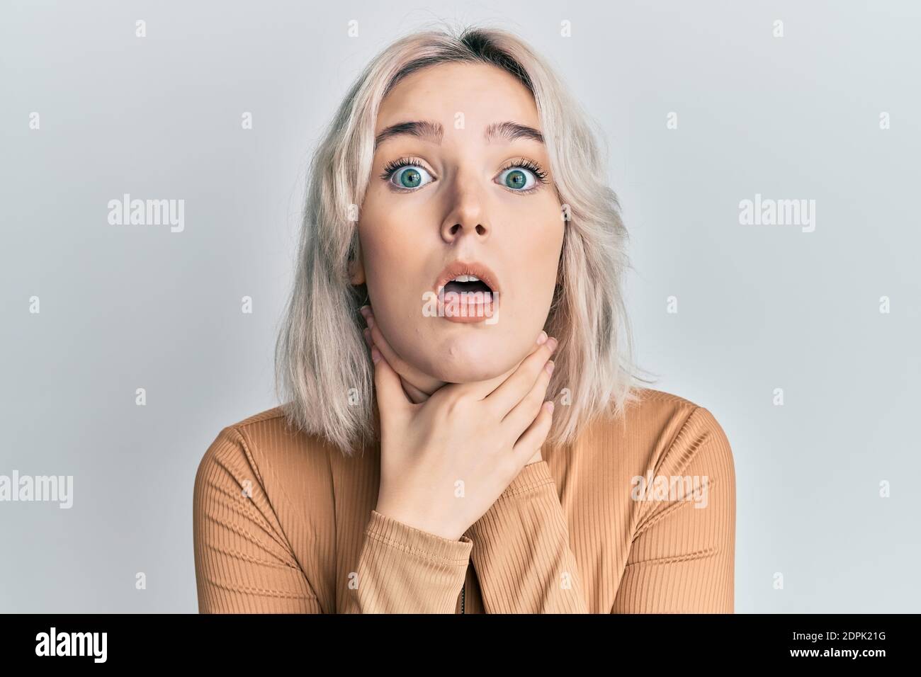 Young blonde girl wearing casual clothes shouting and suffocate because ...