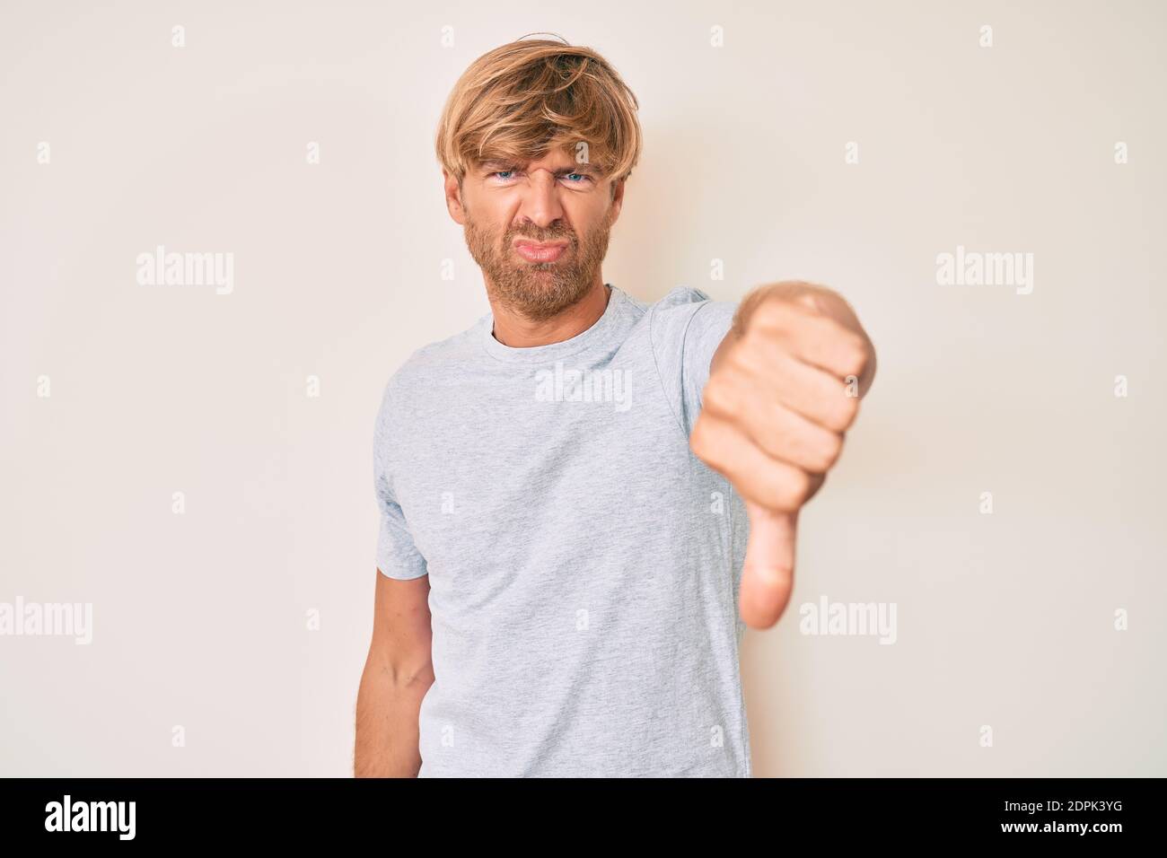 Young blond man wearing casual clothes looking unhappy and angry ...