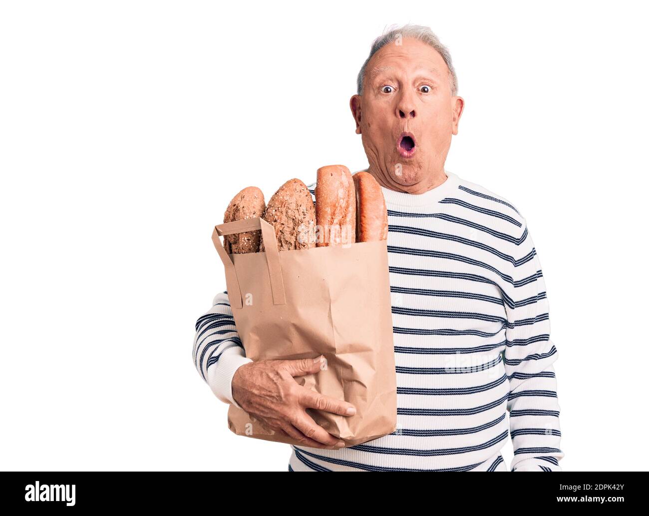 Senior handsome grey-haired man holding paper bag with bread scared and ...