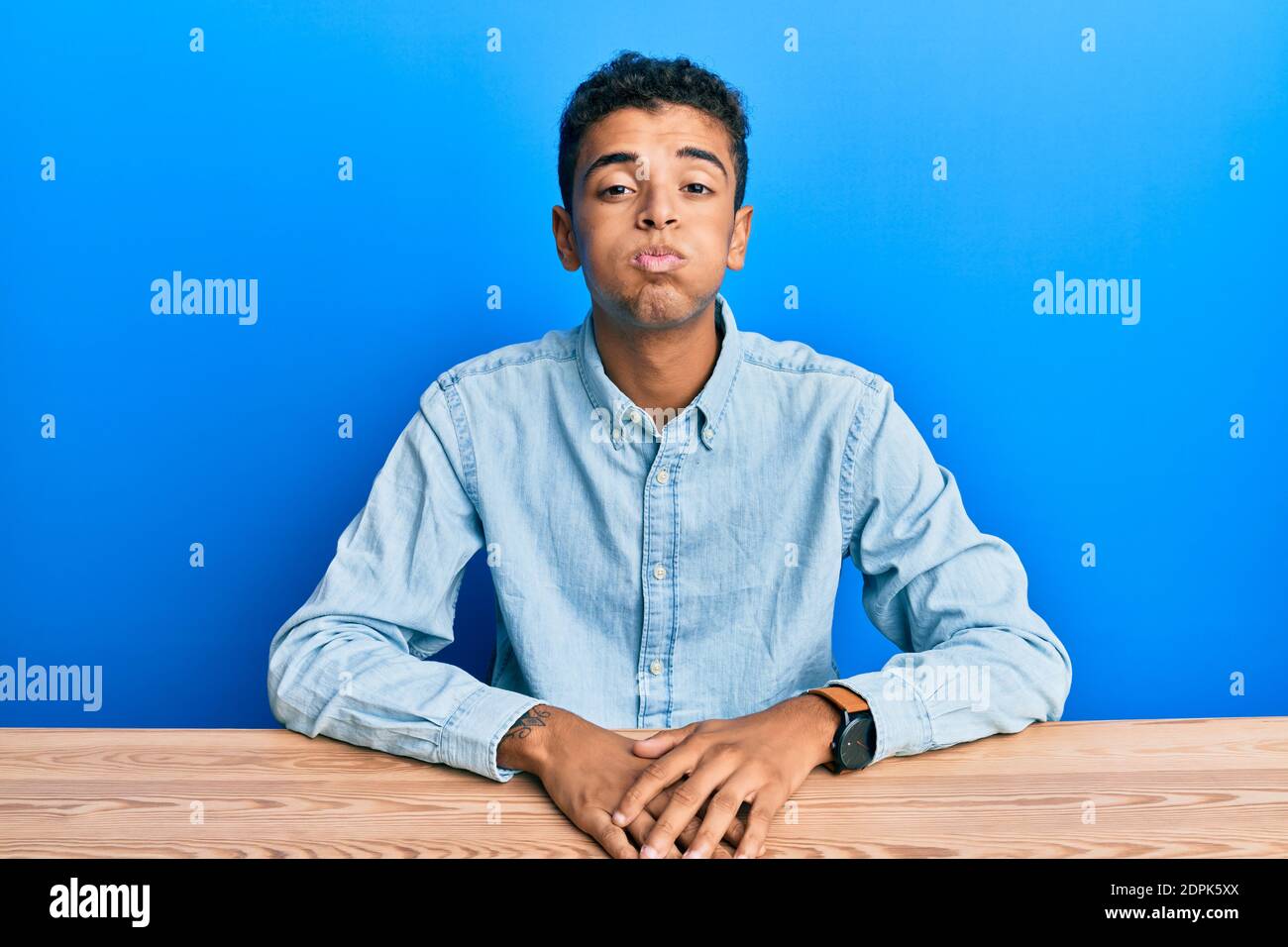 Young handsome african american man wearing casual clothes sitting on ...
