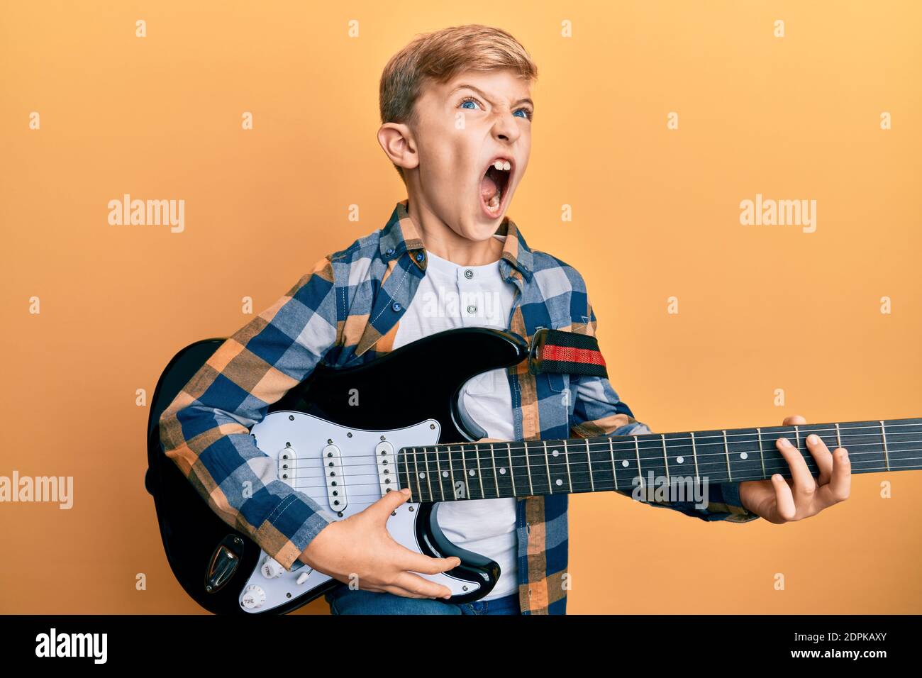 Little caucasian boy kid playing electric guitar angry and mad ...