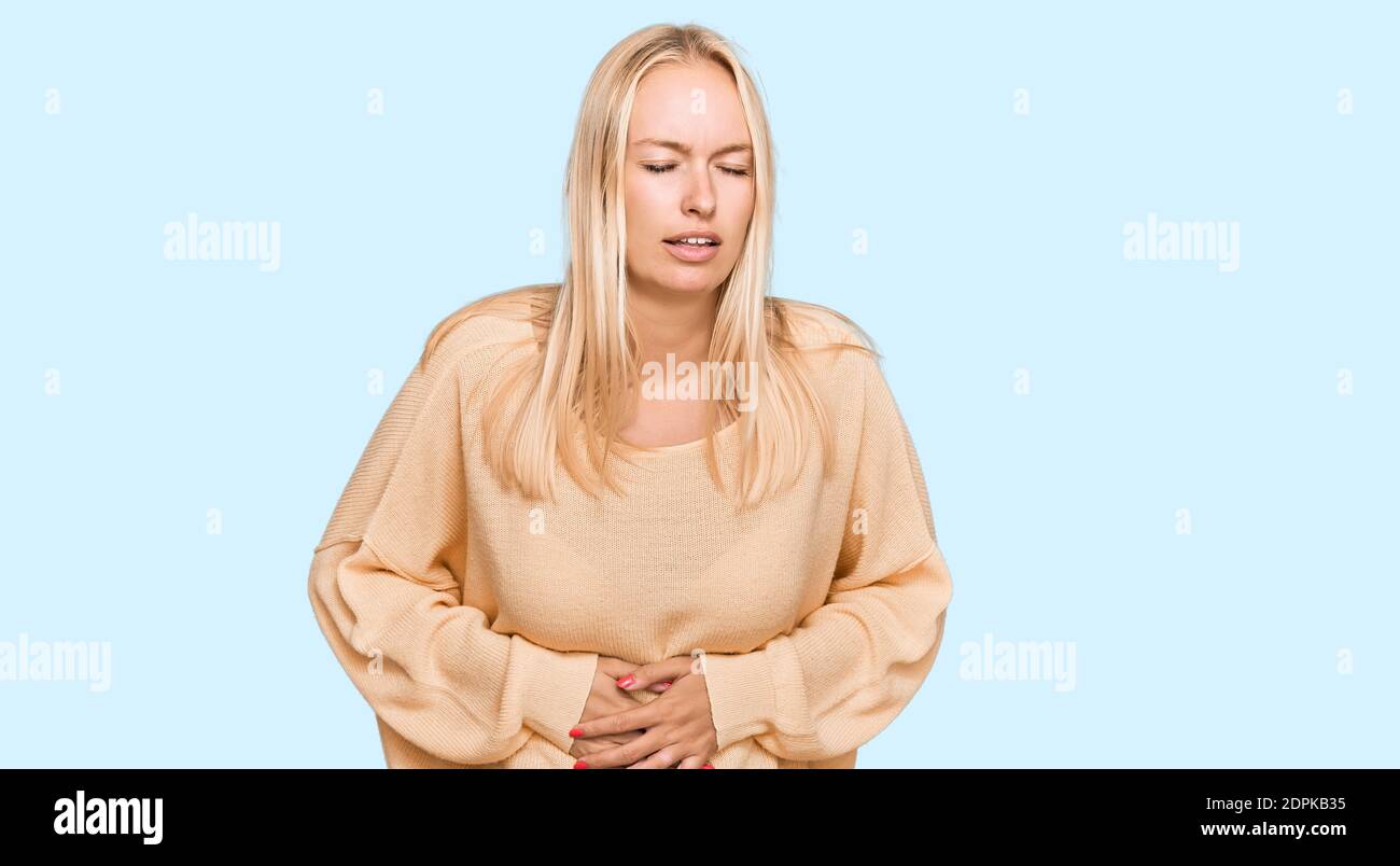 Young blonde girl wearing casual clothes with hand on stomach because ...
