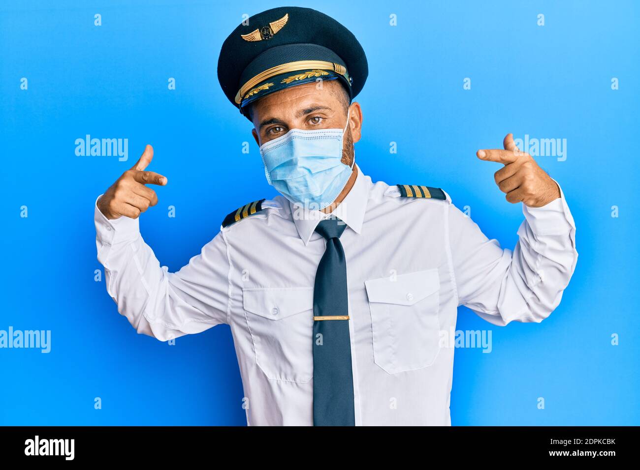 Handsome man with beard wearing airplane pilot uniform wearing safety ...