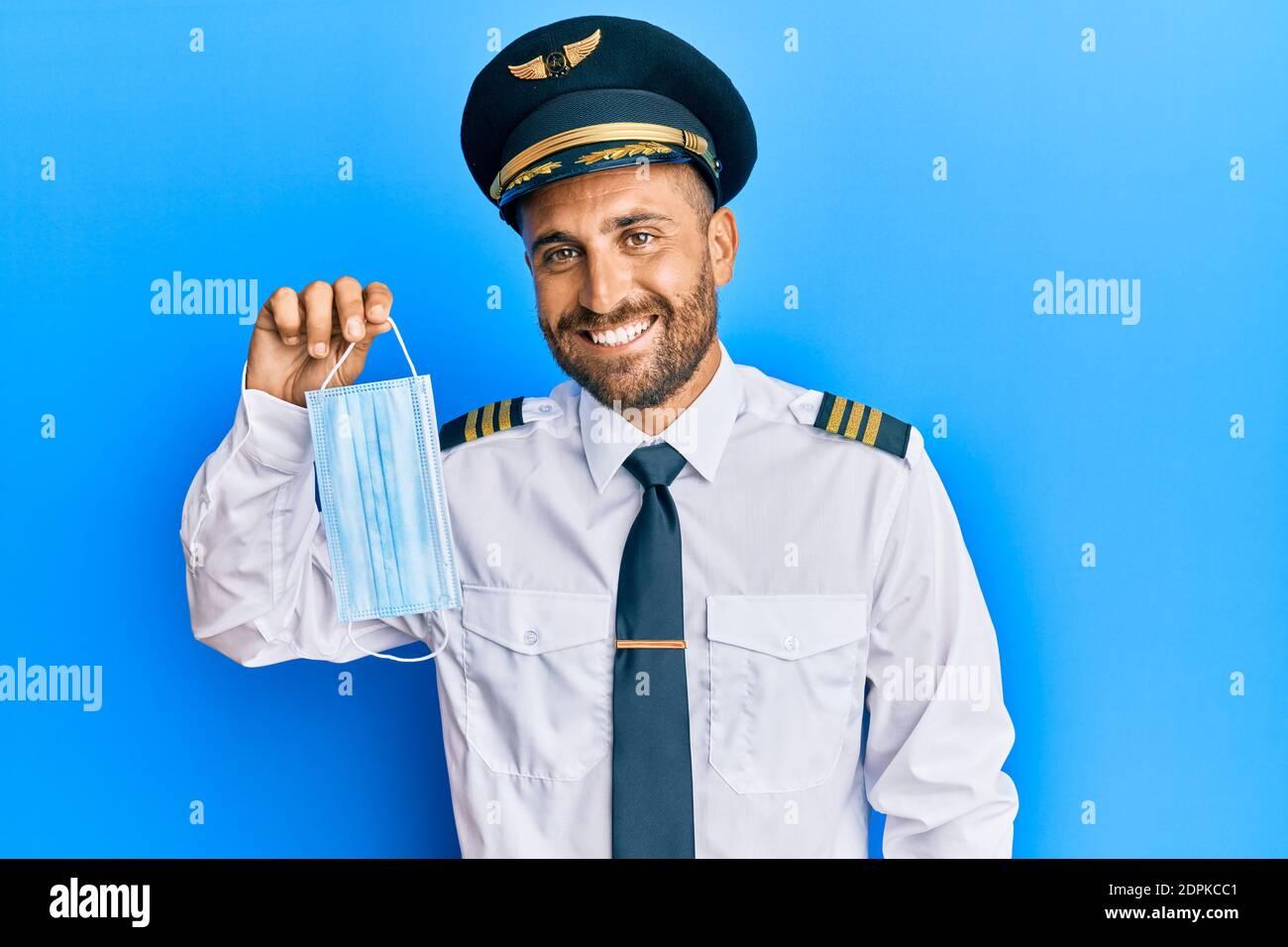 Handsome man with beard wearing airplane pilot uniform holding safety ...