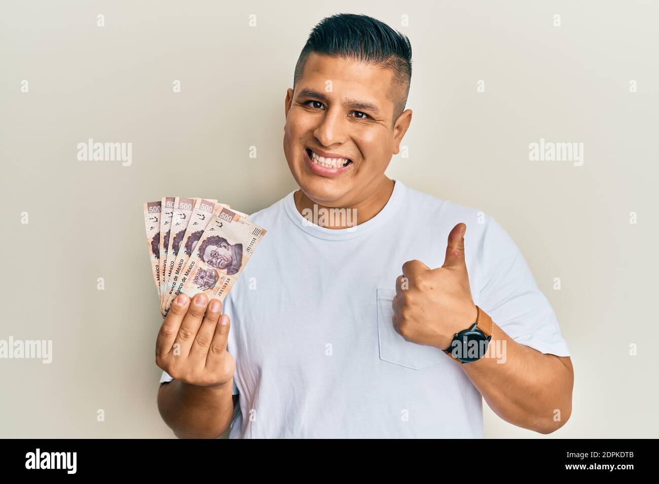 Young latin man holding 500 mexican pesos banknotes smiling happy and ...