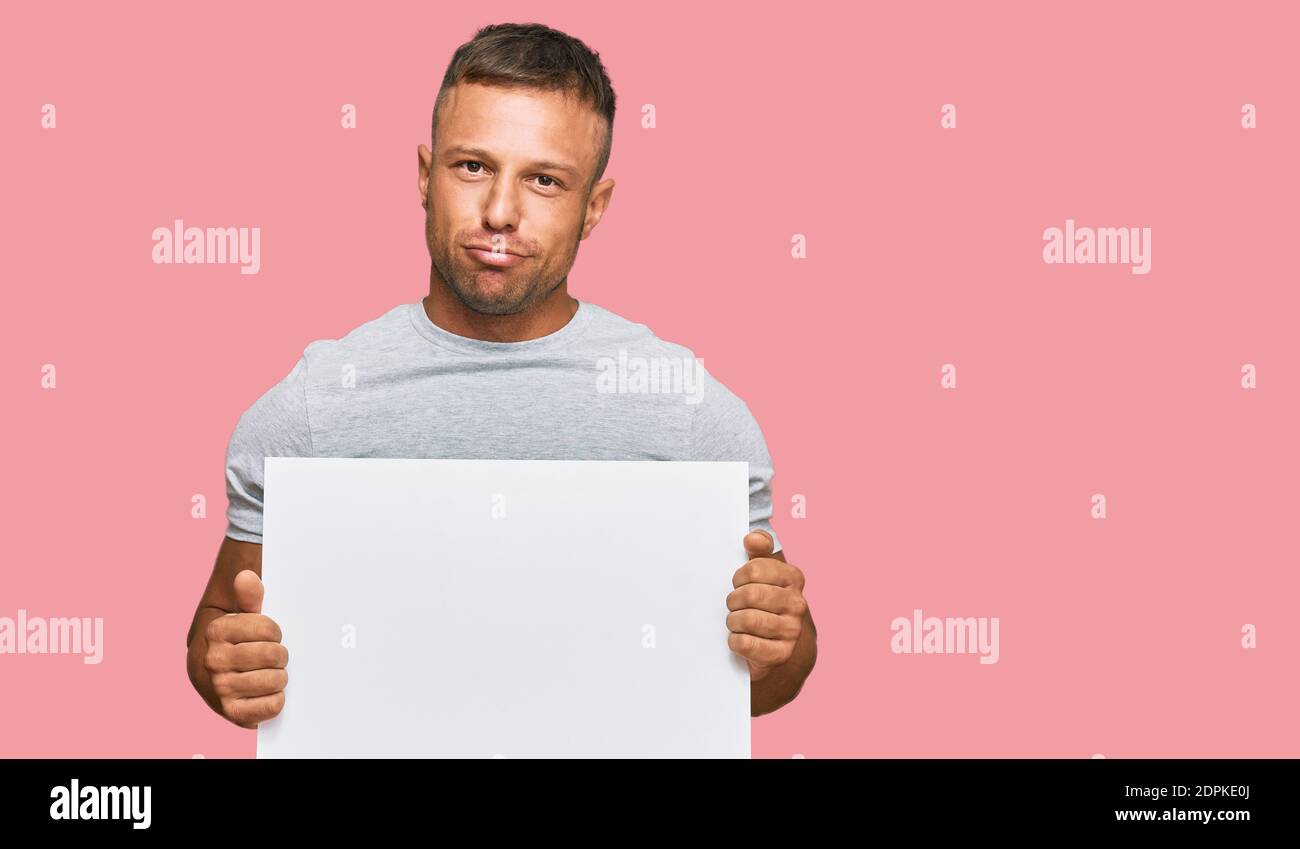 Handsome muscle man holding blank empty banner thinking attitude and ...