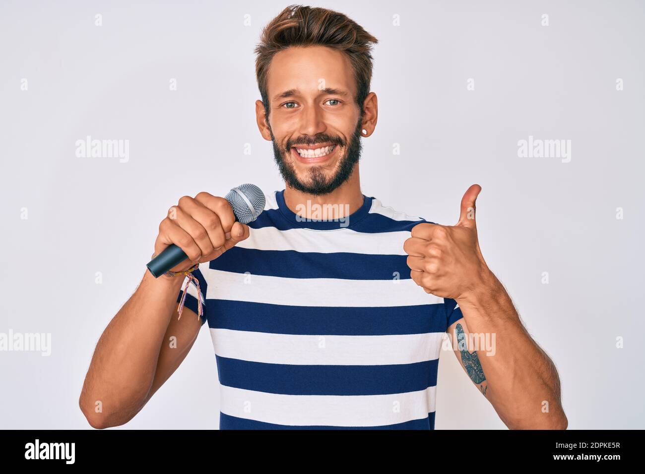 Handsome caucasian man with beard singing song using microphone smiling ...