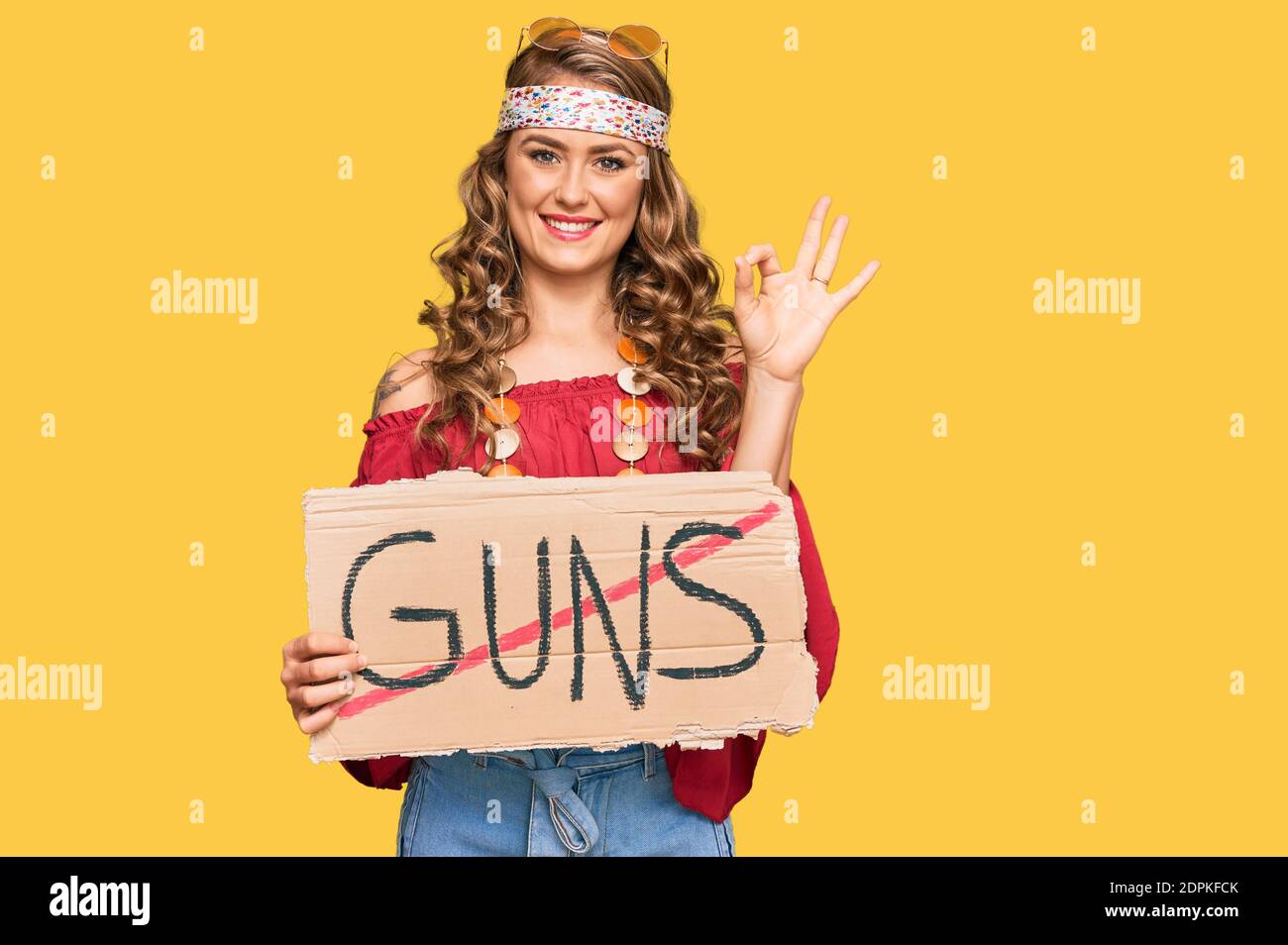 Young blonde girl wearing hippie style holding no guns warning banner ...