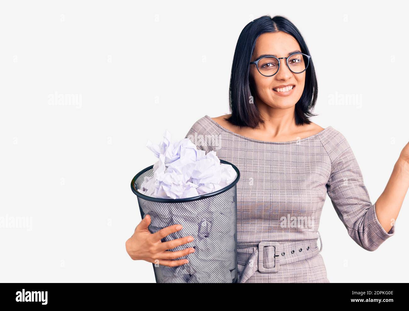 Young beautiful latin woman holding paper bin full of crumpled papers ...