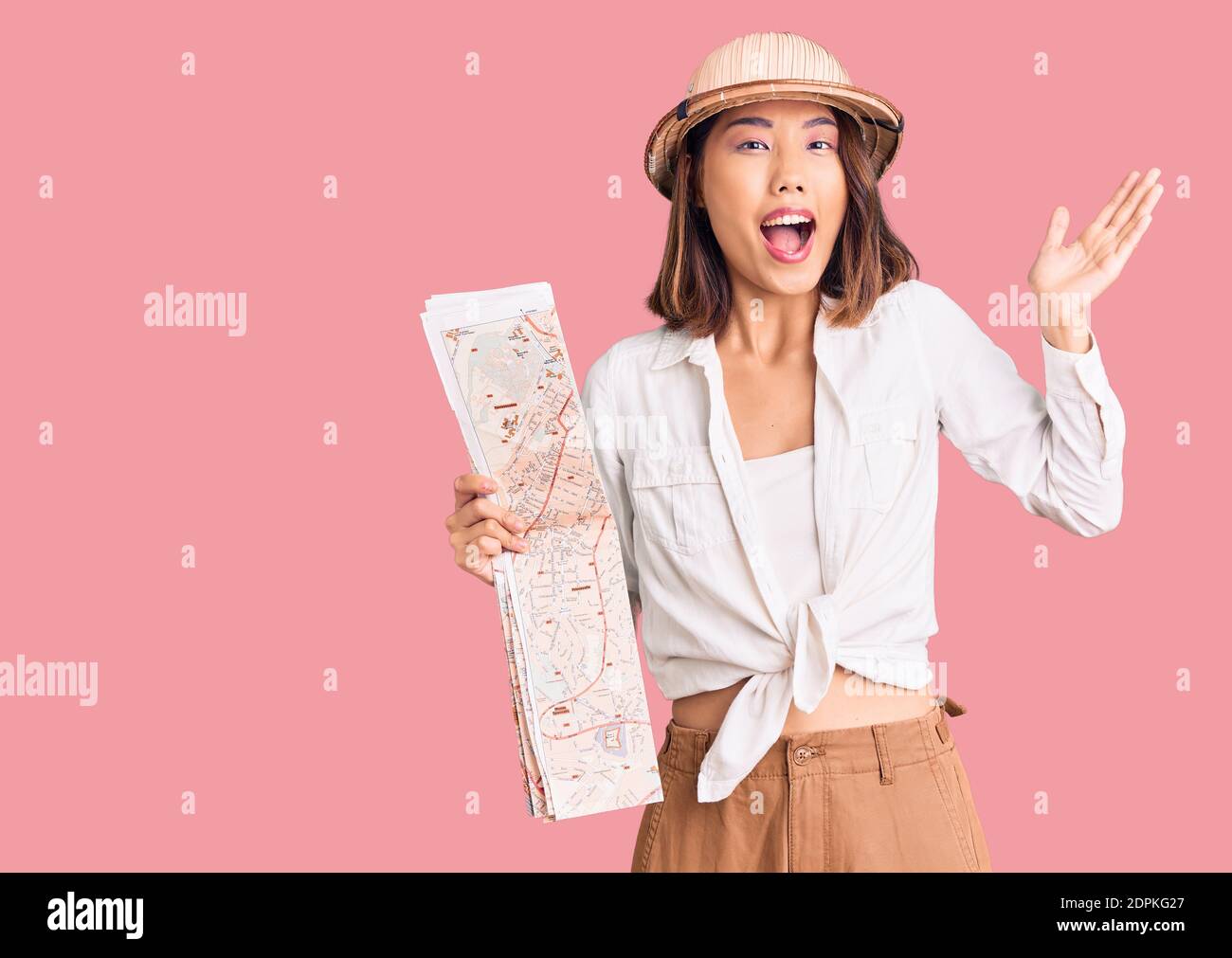 Young beautiful chinese girl wearing explorer hat holding map ...