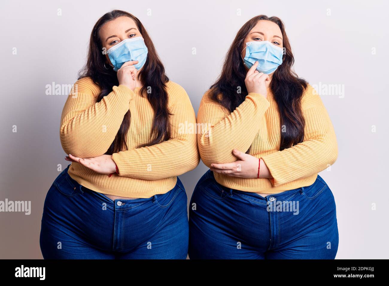 Young plus size twins wearing medical mask looking confident at the ...