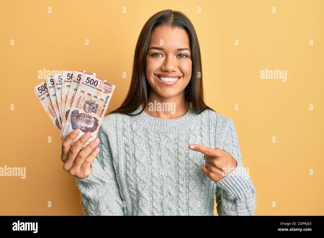Beautiful hispanic woman holding 500 mexican pesos banknotes smiling ...