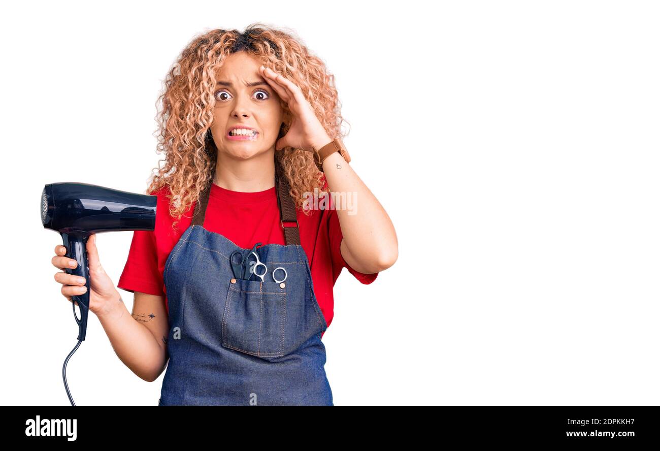 Young blonde woman with curly hair wearing hairdresser apron and ...