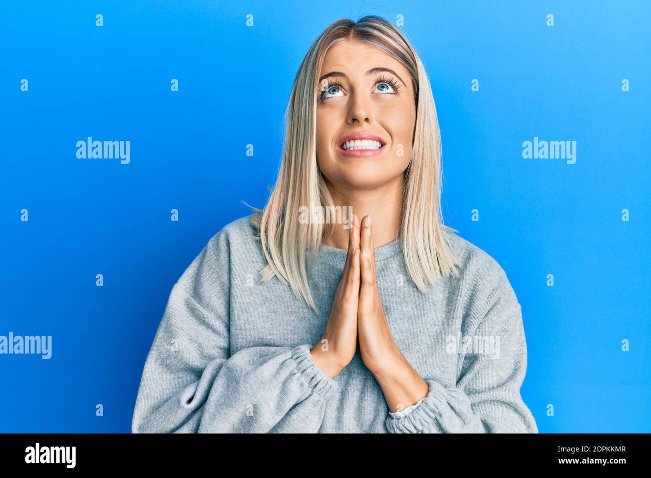 Beautiful blonde woman wearing casual clothes begging and praying with ...