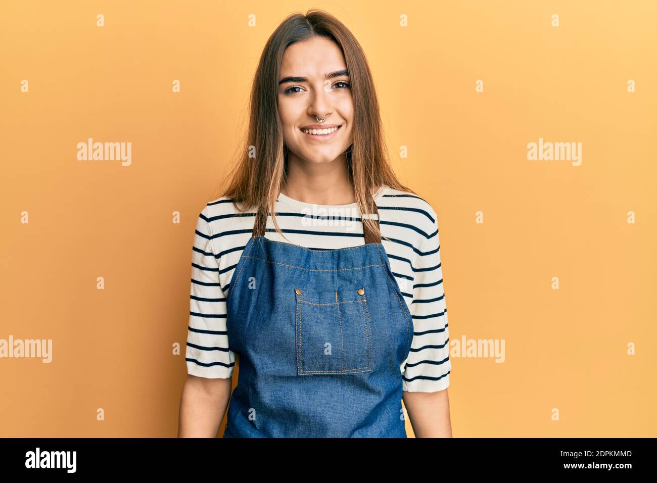 Young hispanic woman wearing barber apron looking positive and happy ...